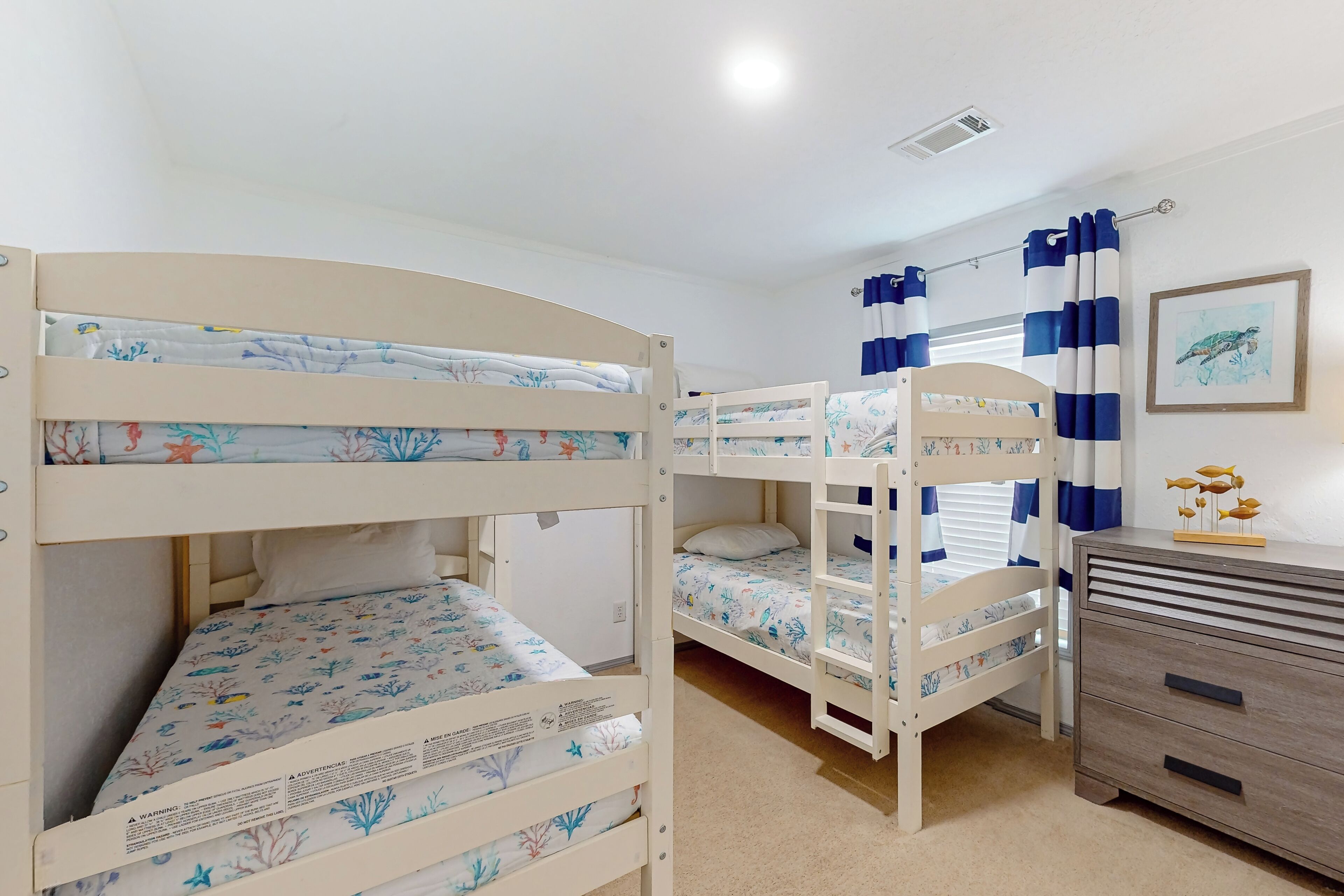 Quarto com beliche, cômoda de madeira e quadro pendurado na parede.