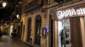 Vista noturna de uma rua com uma loja boutique chamada "SAPIA STO", com um manequim na vitrine.
