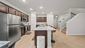 Uma cozinha moderna com uma ilha central, eletrodomésticos de aço inoxidável e um espaço de jantar com banco.