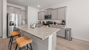 Cozinha moderna com ilha central, eletrodomésticos de aço inoxidável e design minimalista.