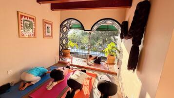 Quarto com varanda, tapetes de yoga e plantas em vasos.
