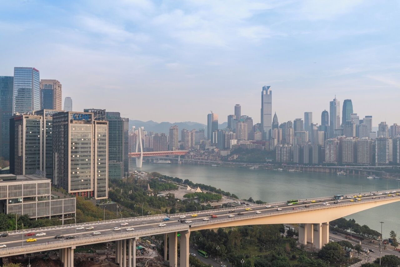 Paisagem urbana com edifícios altos modernos, um rio e uma ponte.