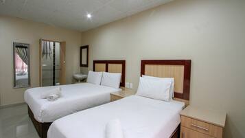 Quarto de hotel com duas camas, um banheiro e um espelho.
