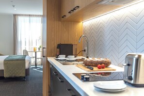 Cozinha de hotel moderna com backsplash em padrão herringbone, pão, tomates e cafeteira.