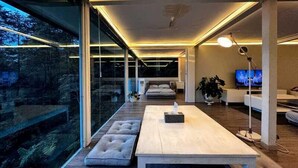 Uma sala de estar moderna com uma grande parede de vidro, uma mesa de madeira e um sofá.