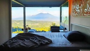 Um quarto com uma cama grande, vista para uma montanha e um painel decorativo na parede.
