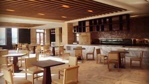 Restaurante moderno com mesas e cadeiras de madeira, painel de parede de pedra e uma grande TV de tela plana.