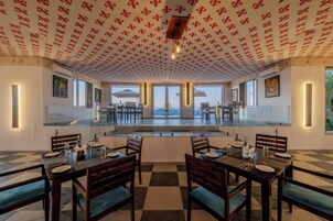 Uma sala de jantar com piso xadrez, mesas e cadeiras de madeira.
