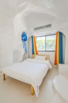 Quarto com cama, cadeira, janela com cortinas e ar condicionado.