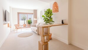 Uma sala de estar moderna com sofá, mesa de jantar, televisão e uma planta grande.