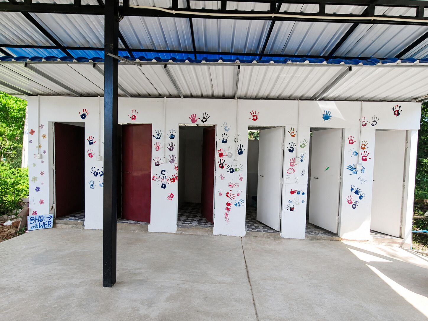 Uma área externa coberta com várias portas, cada uma decorada com coloridas impressões de mãos.