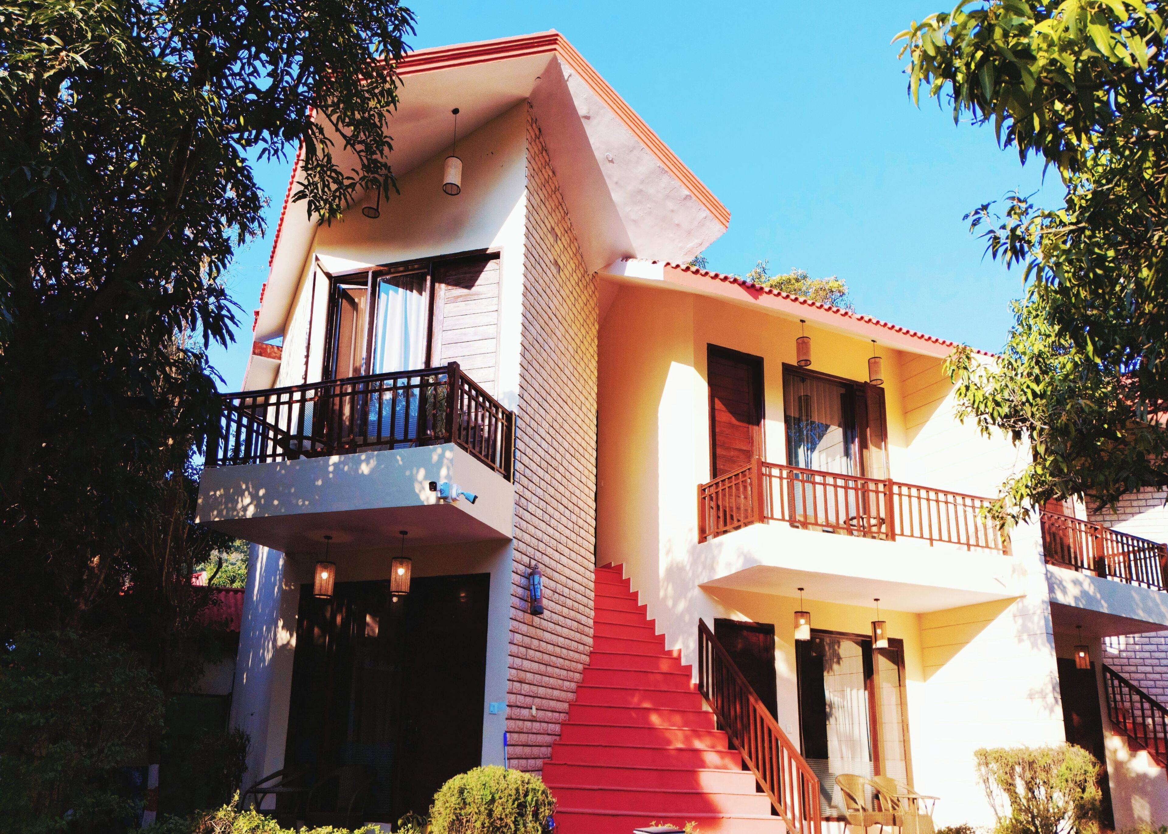 Um edifício de dois andares com uma escadaria vermelha que dá para uma varanda.