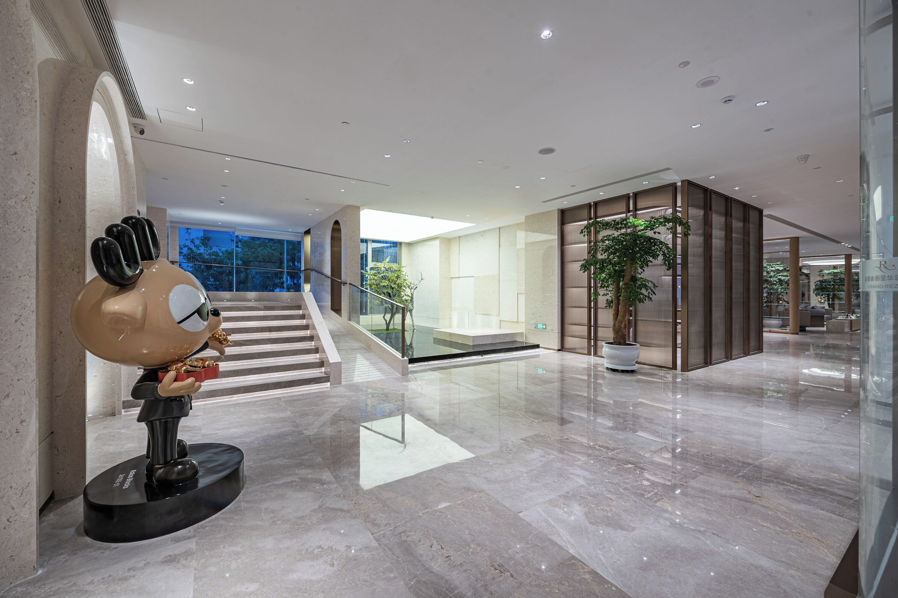 Um hall moderno com piso de mármore, escada e uma grande planta em vaso.
