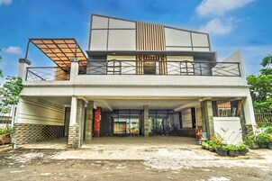 Um edifício moderno de dois andares com telhado plano, janelas amplas e área de entrada coberta.