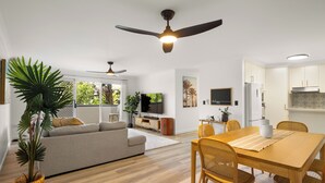 Uma sala de estar moderna com sofá, mesa de jantar, cadeiras e ventiladores de teto.
