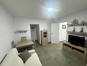 Um espaço compacto para viver, com sofá, mesa de jantar, televisão e armário.