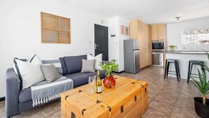 Uma sala de estar moderna com sofá, mesa de centro e área de cozinha com armários e eletrodomésticos.