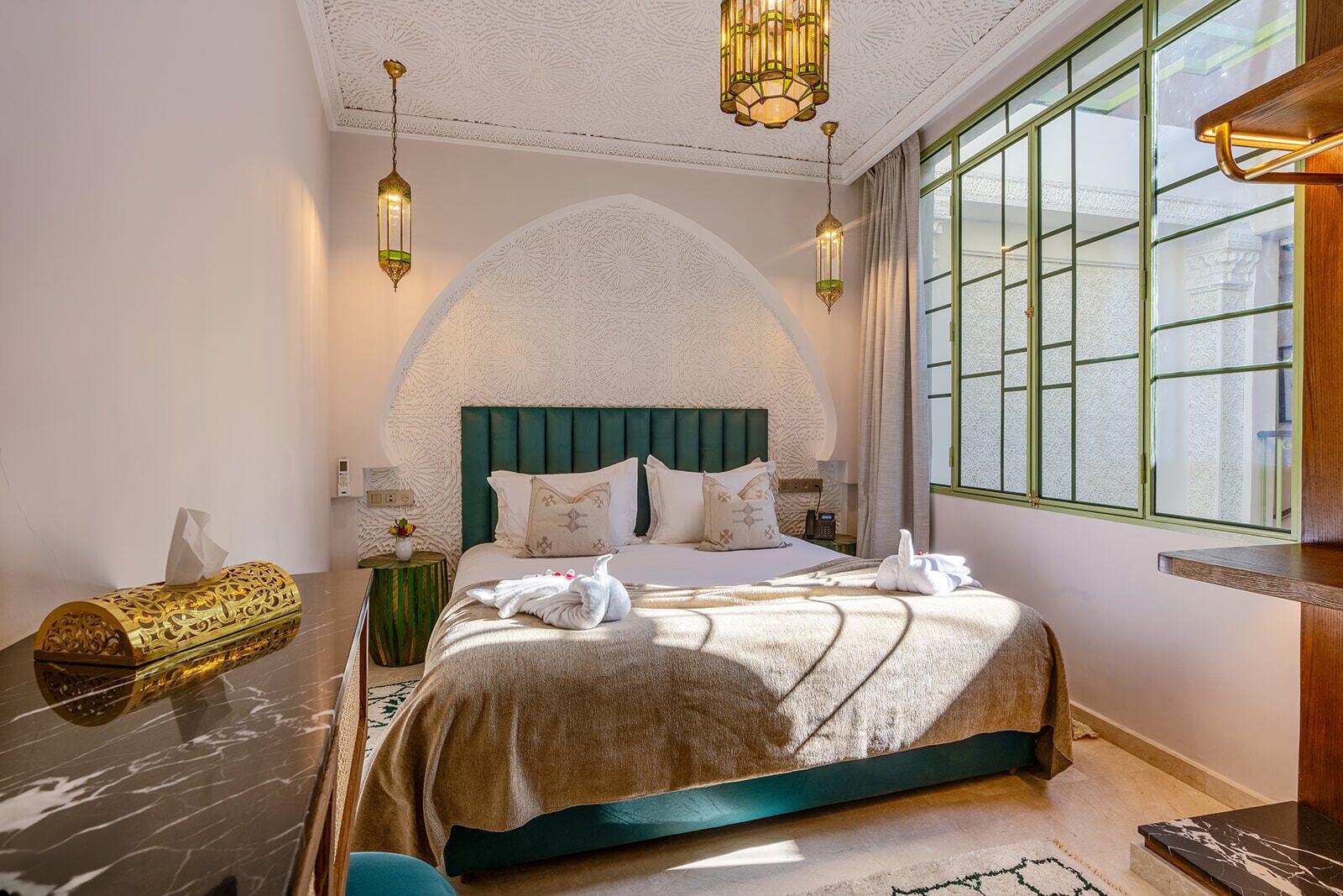 Quarto espaçoso com uma cama grande, piso de mármore e vista pela janela com molduras verdes.