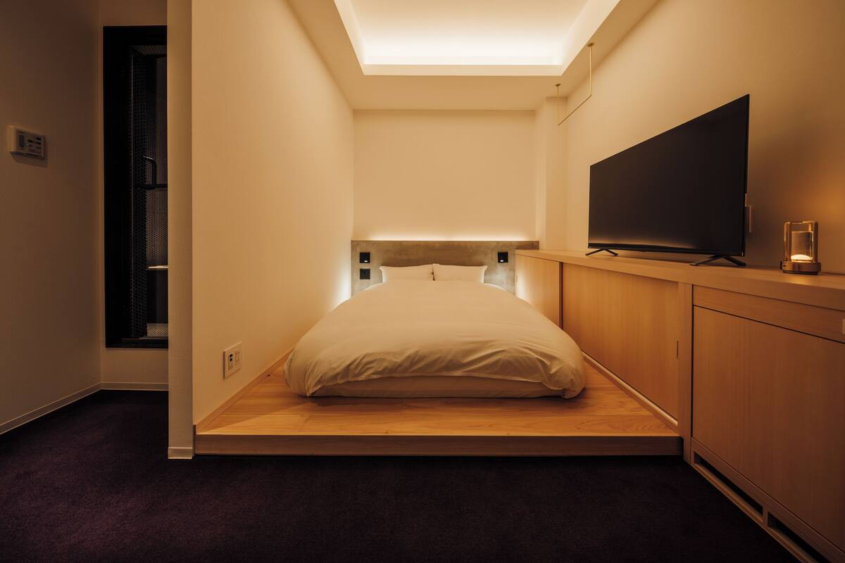 Quarto moderno com claraboia, televisão de tela plana e design minimalista.