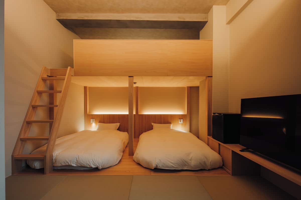 Quarto com beliche, televisão e escada de madeira.