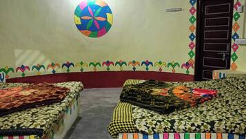 Quarto com duas camas, um ornamento de parede colorido e uma borda estampada.