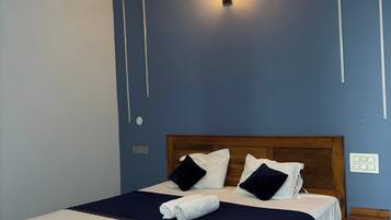 Uma cama bem arrumada com cabeceira de madeira, um ventilador de teto e uma luminária fixa na parede.