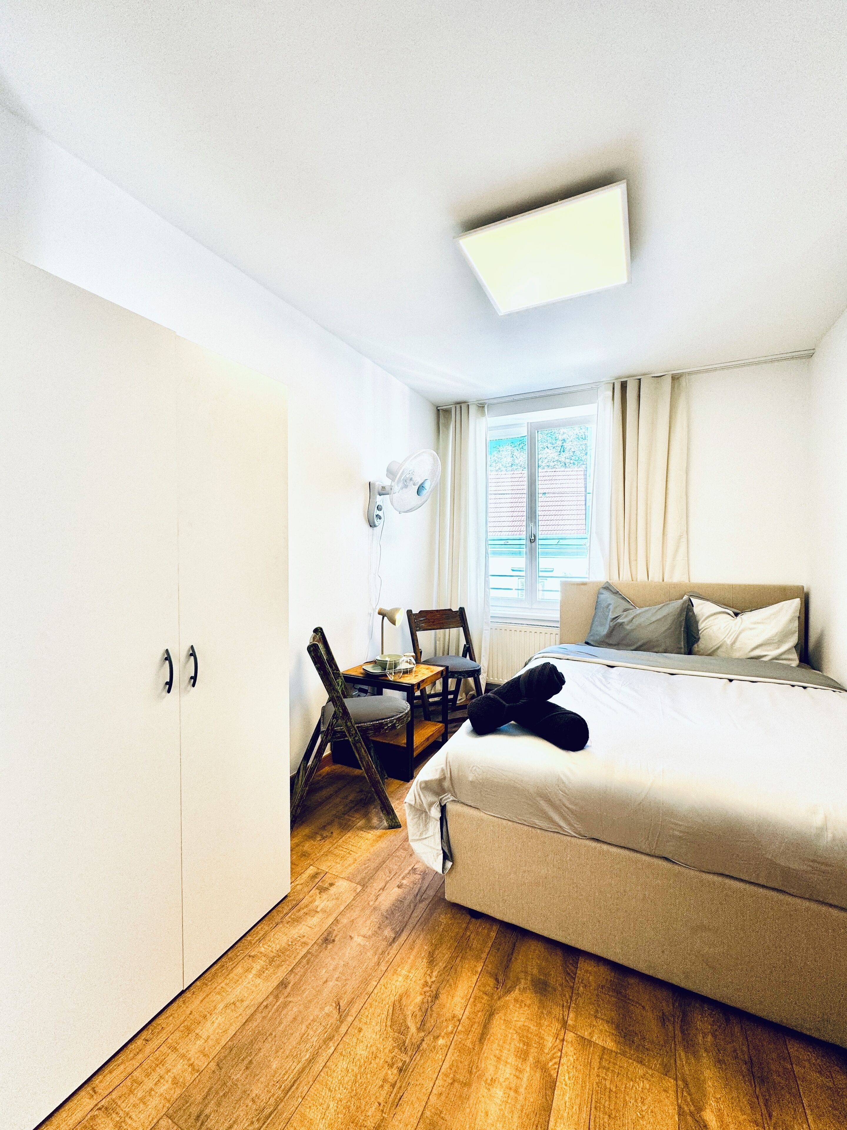 Um quarto com uma cama, uma escrivaninha, uma cadeira e um guarda-roupa.
