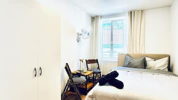 Um quarto com uma cama, uma escrivaninha, uma cadeira e um guarda-roupa.
