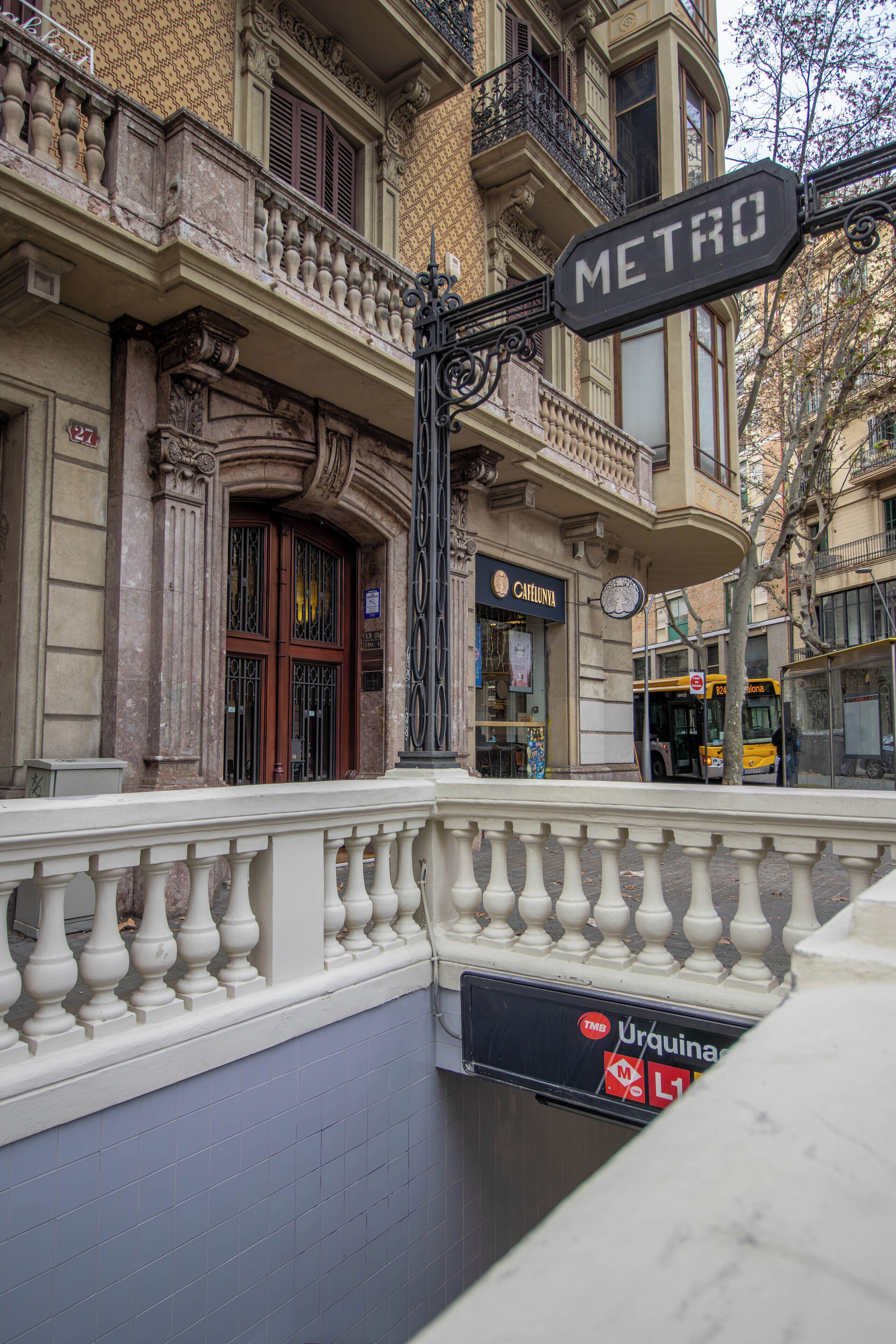 Sinal de metrô acima da entrada de um edifício com varandas ornamentadas e uma loja com a inscrição 'CATALINA'.