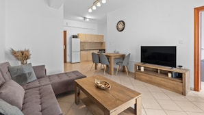 Uma sala de estar moderna com um sofá seccional, uma mesa de centro de madeira e uma TV sobre um suporte de madeira.
