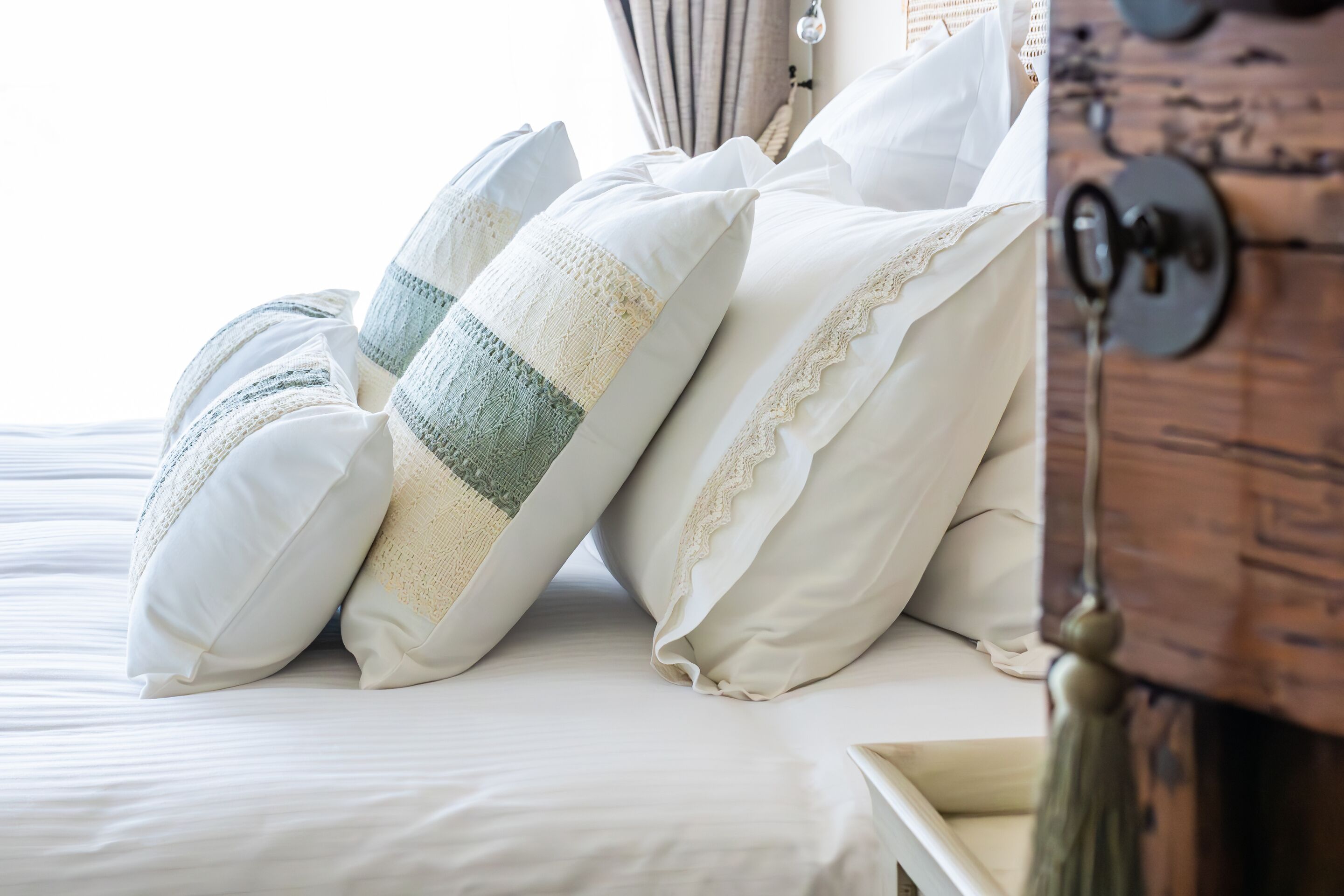 Cama com roupa de cama branca e almofadas decorativas.