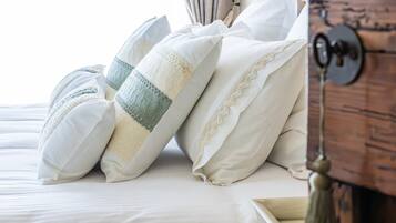 Cama com roupa de cama branca e almofadas decorativas.