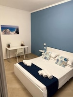 Quarto com cama, escrivaninha e cadeira.