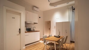 Uma cozinha moderna com armários brancos, bancada de madeira e uma área de refeições com mesa e cadeiras.