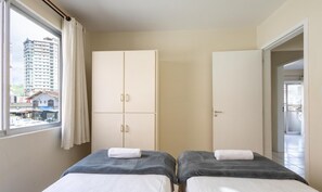 Quarto de hotel com duas camas, um guarda-roupa e vista para a cidade.