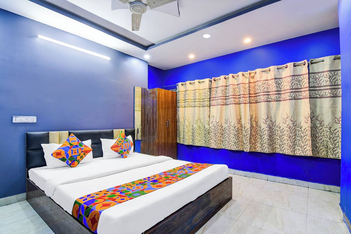 Quarto com cama, ventoinha no teto e parede com cortinas.