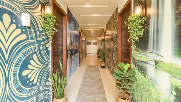 Um corredor com paredes estampadas, plantas em vasos e vista para um espelho d'água.
