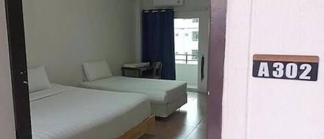 Quarto com duas camas, uma mesinha e uma cadeira. Há uma placa na parede com o número A302.