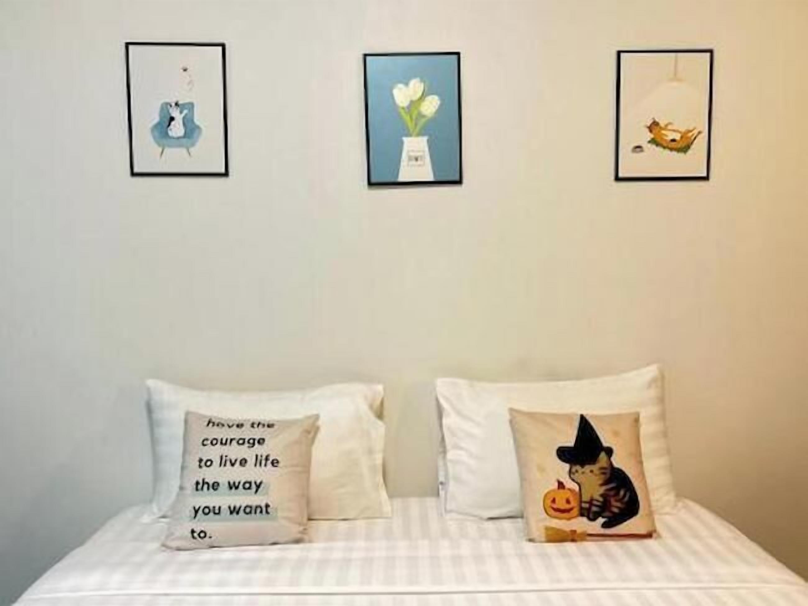 Quarto com cama, duas almofadas e três quadros na parede.