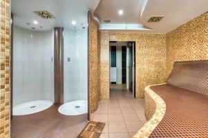 Casa de banho moderna com um banco curvo, zona de duche e chão em mosaico.