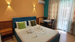 Quarto de hotel com uma cama grande, uma escrivaninha e duas unidades de ar condicionado fixadas na parede.