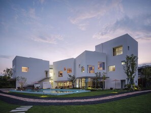Uma casa moderna de vários andares com piscina, área de estar externa e jardim bem cuidado.