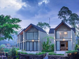 Uma casa moderna de dois andares, com amplas janelas, um caminho de pedra e vegetação exuberante.