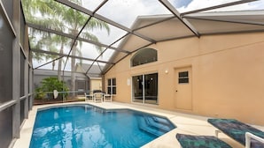 Piscina interior com teto de vidro, espreguiçadeiras e porta que dá para uma área coberta.