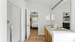 Uma casa de banho moderna com chuveiro, lavatório e espelho.