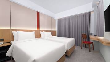 Quarto de hotel com duas camas, uma mesa, uma cadeira e uma televisão.