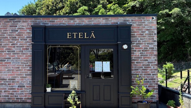 Um edifício de tijolos com uma entrada escura identificada com 'ETELÀ'.