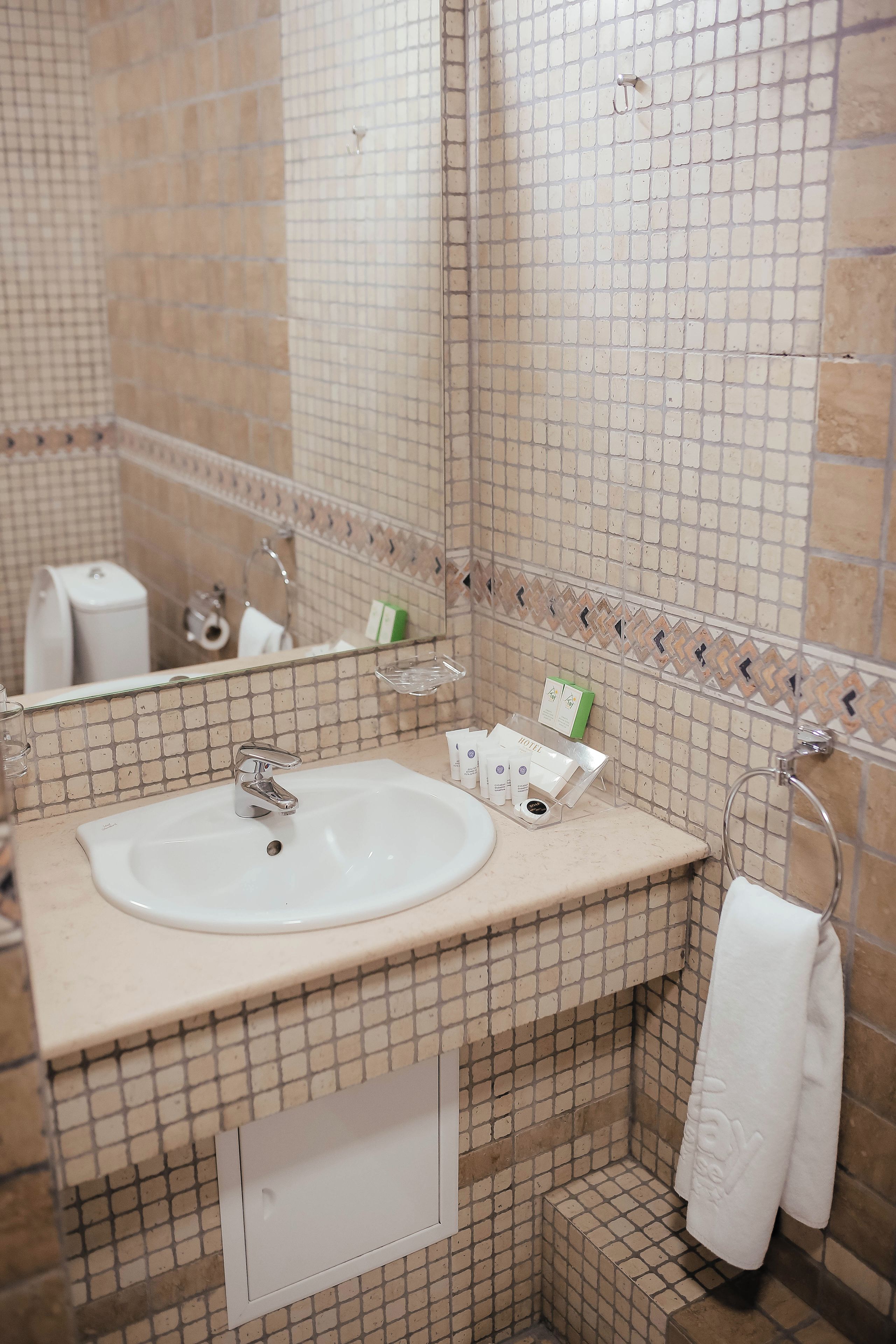 Casa de banho com lavatório branco, espelho e porta-toalhas.