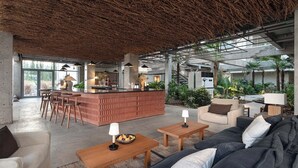 Um espaço amplo e interno, com um bar central, áreas de estar e grandes janelas que permitem entrada de luz natural.