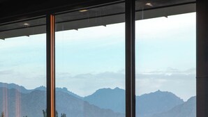 Quarto moderno com uma janela grande que dá para uma paisagem montanhosa.